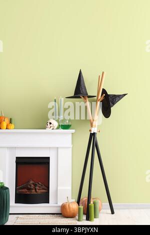 White fireplace with Halloween pumpkins and decorations near green wall ...