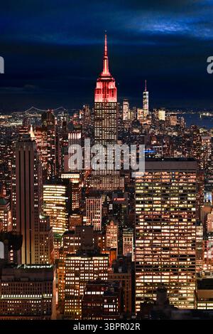 A tall, illuminated office building with glowing windows at night ...