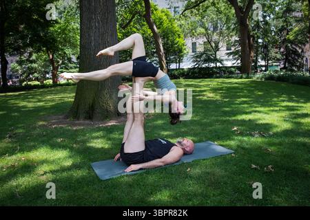 A graceful attractive lady performs Acroyoga, a practice that combines ...