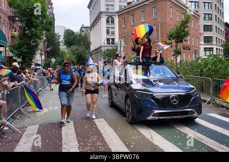A crowd of participants with rainbow and other LGBTQ+ flags marches ...