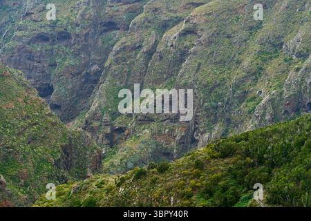 Eroded cliffside with visible caves and stratified volcanic rock in ...