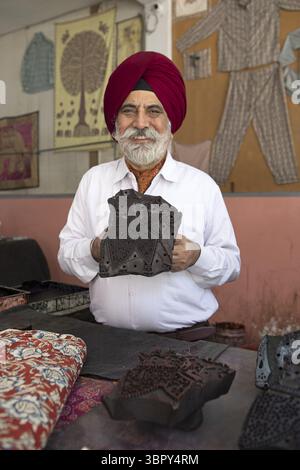 Indian Sikh, 68 years old, in his shop, in front bales of cloth and ...