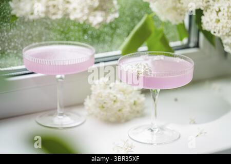 Fresh pink non alcoholic cocktail in glass with lilac flowers against ...