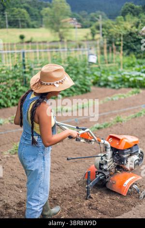 Young woman tractor straw hat rural field plaid shirt overall boot ...