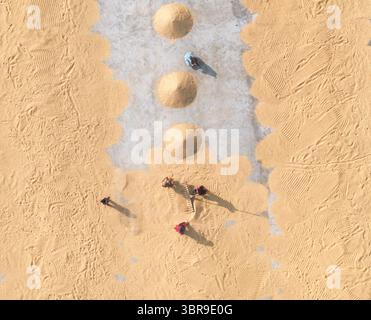 Rice harvest spread out on a bamboo mat next a road for drying in the ...