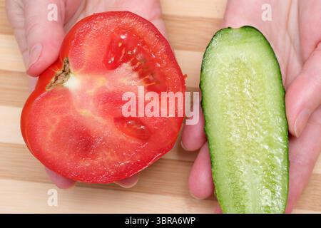 A person holds a bright red tomato in their hands while standing in a ...