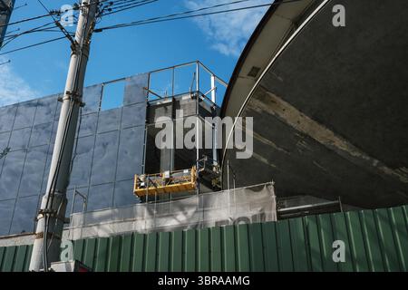 Workers labor on a scaffolding to install insulation layers on a ...