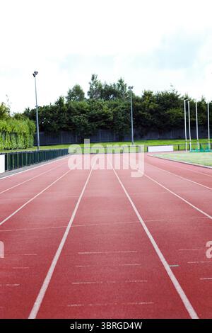 Red synthetic running track is stretching across flat stadium scene ...