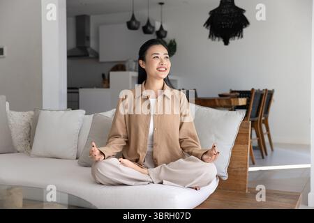 Happy Asian woman sits on wooden balcony terrace with cute small cat ...