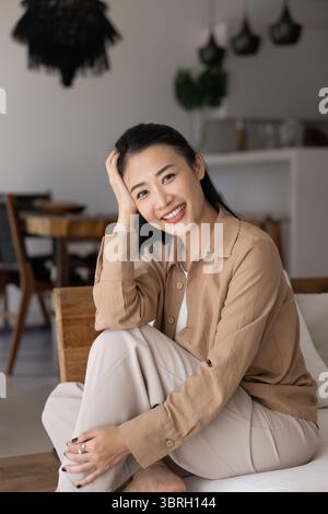Asian woman relaxing on couch at home drinking coffee while playing ...