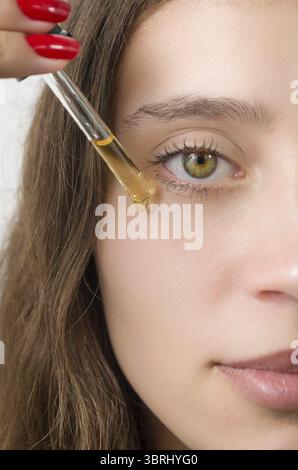 young woman applying serum on shiny hair isolated on grey Stock Photo ...
