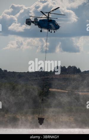 A helicopter performs a water drop during a wildfire to help control ...