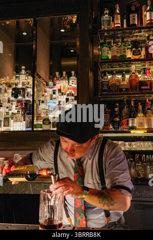 Male bartender pours a drink into a glass with ice. Barman at the bar ...