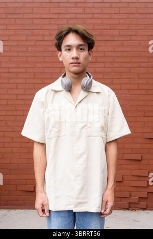 Non binary cute Asian young gay man portrait against plain background ...