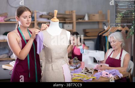 Mature head of manufacturing and female assistant sewing, young ...