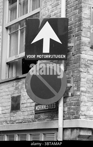 A sign pointing to parking located on a post next to a fence with a ...