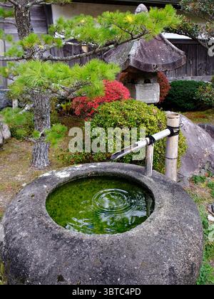 Traditional ancient Japanese Tsukubai stone water basin with bamboo ...