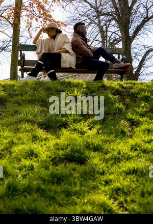 A couple is sitting in a autumn colored park and enjoy the regenerating ...