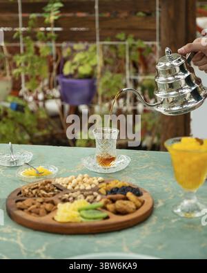 Pouring of hot Turkish tea from teapot into glass on wooden table Stock ...