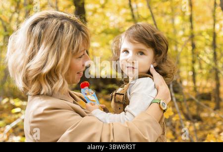 Mother with child in her arms against background of autumn nature ...