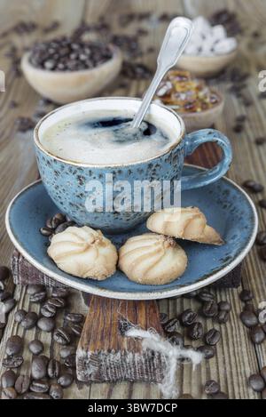Sweet cookies and coffee in blue dishes on black stone background, top ...