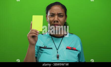 Referee holds yellow card toward camera in green studio with serious ...