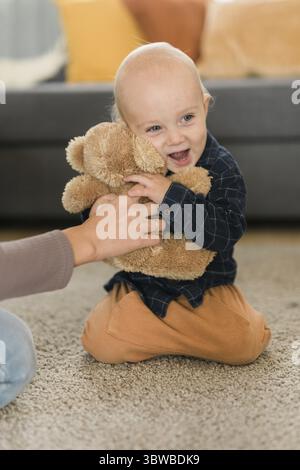 Happy toddler boy playing with her teddy bear at house - childhood and ...