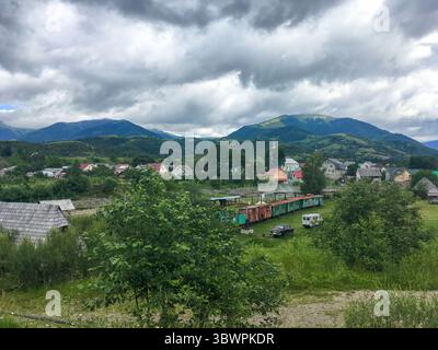 Lush green landscape with hilly terrain, scattered trees, and a few ...