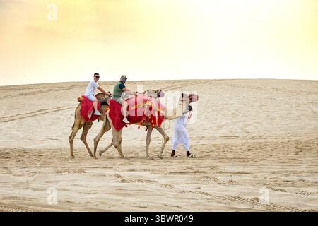 Tourists riding camels in the sealine dunes Qatar Stock Photo - Alamy