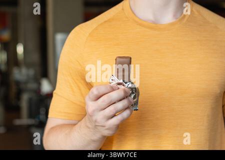 Sporty man eating energy bar. Muscular athlete snacks protein bar while ...