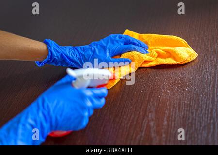 Hands in yellow gloves wipe surface of black induction stove close up ...