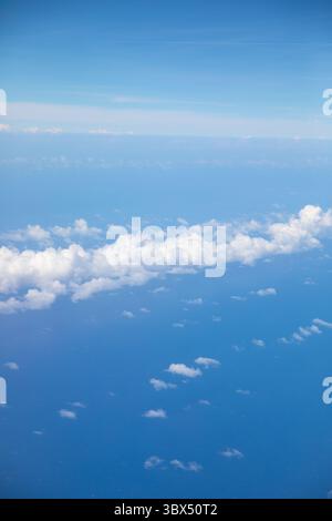 Fluffy white clouds drift across a vibrant blue sky over fields Stock ...