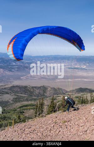 A paraglider pilot runs to launch his paraglider off the top of Monroe ...