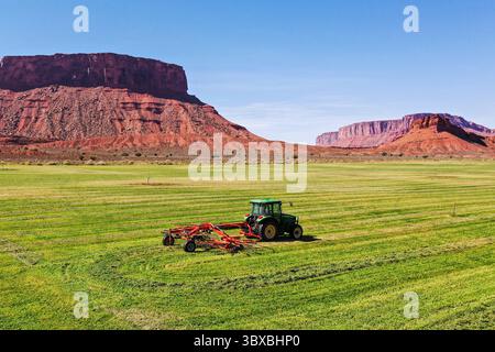 A rotary rake combining smaller windrows of hay into one larger row for ...