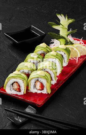 Red plate with sushi, filled with rolls of different kinds, next to ...