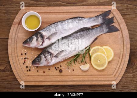 Two fresh moronidae fish on cutting board with ingredients, top view ...