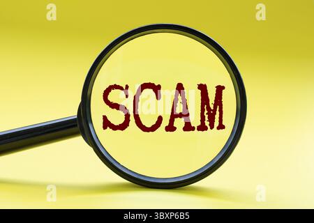 Magnifying glass focusing on SCAM text on yellow cover background ...