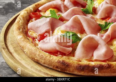 Closeup of pizza with melted mozzarella, ham, quail eggs, tomatoes and ...