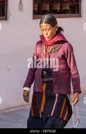 An older Tibetan woman pilgrim circumambulates the Jokhang Temple with ...