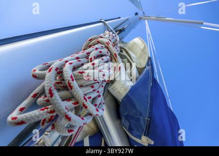 Bottom view of mast and sail of yacht on blue sky background, selective ...