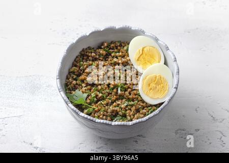 Cooked buckwheat in a bowl, garnished with fresh parsley, on a purple ...