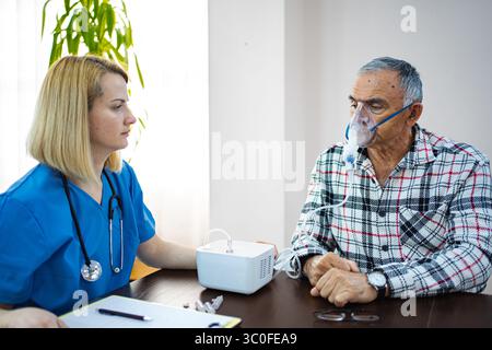 A senior man receives respiratory treatment with a medical device ...