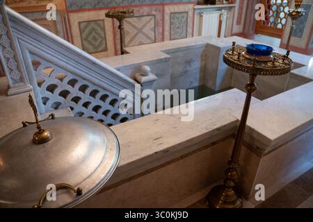 Sacred orthodox baptism font stands near bright stained glass window ...