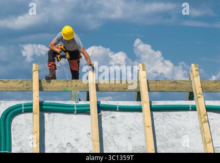 Worker places wooden beams on roof frame in construction area Stock ...