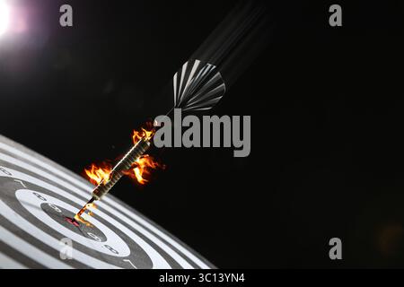 Dart with flames hit center of target against black background, motion ...