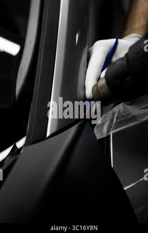 Car Wrapping with Trim Tool. Car detailing applies vinyl wrap around ...