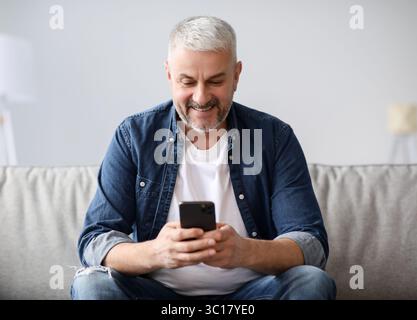 Senior grey haired gamer man playing video games using gamepad joystick ...