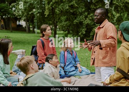 Primary school teacher engaging a group of students in a collaborative ...