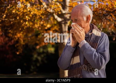 Senior man blowing his nose, blurred background Stock Photo - Alamy