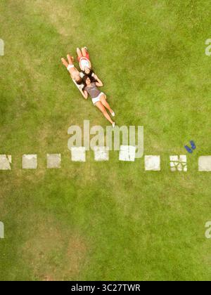 Aerial view of three girls lying in the garden during summer Stock ...